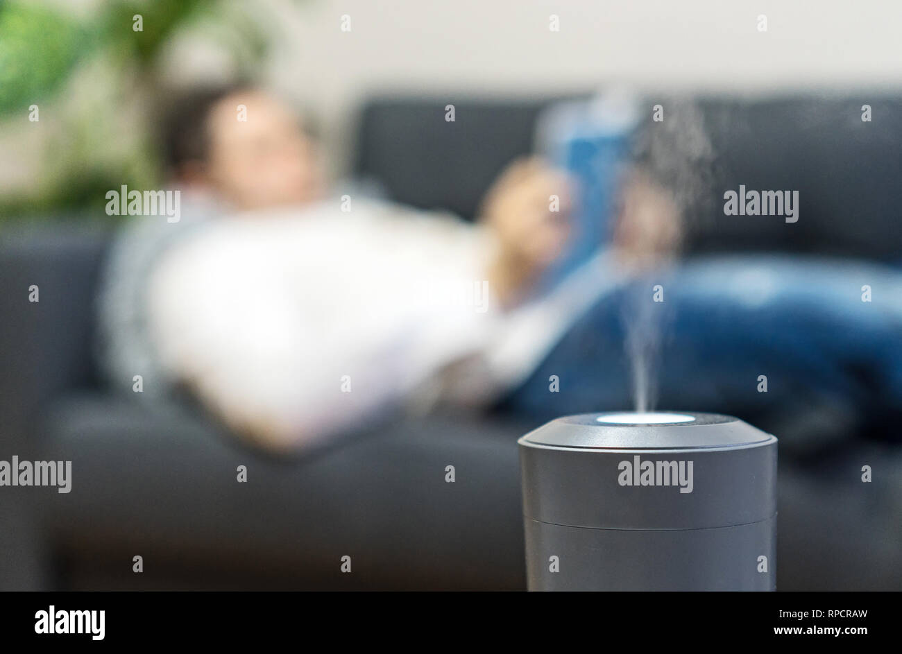 Air humidifier at living room. Man reading book on the background Stock ...