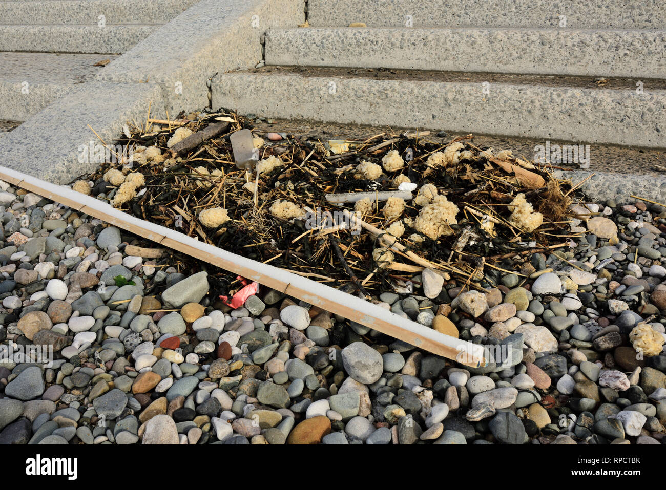 Rubbish washed up against stone stepped revetment on shingle beach in ...