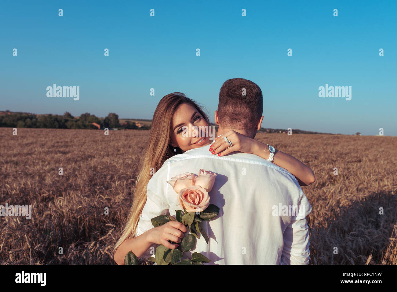 Girl with long hair happy hugging man holding roses behind back gift ...