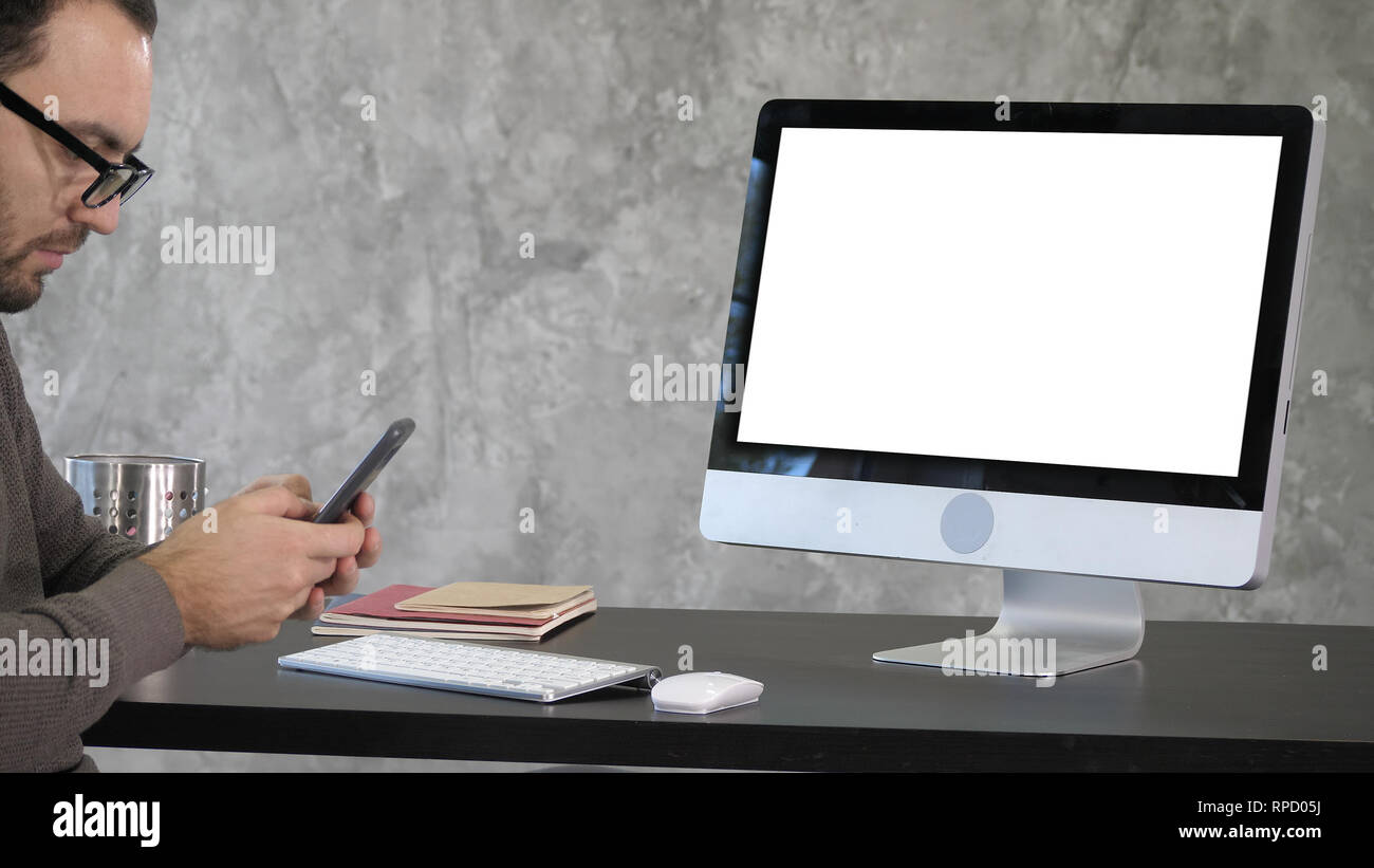 View to the screen of computer. Young man texting on the phone with a ...