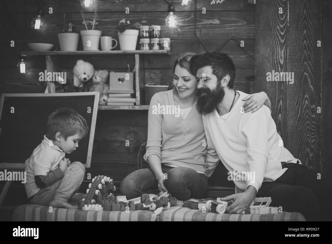 Happy parents hug each other while looking at son. Family playing with ...