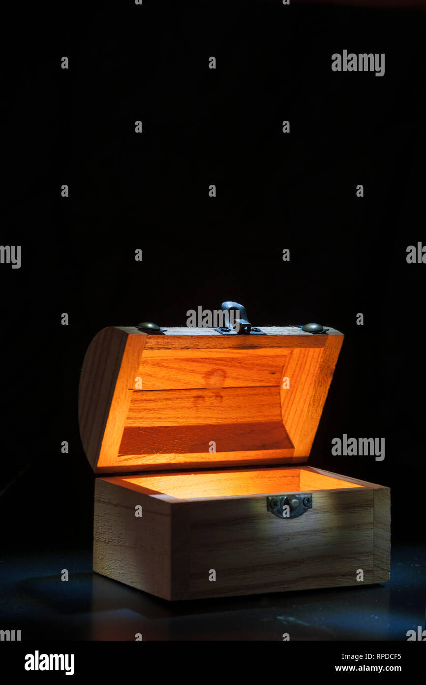 Small wooden chest inside illuminates against a black background Stock ...