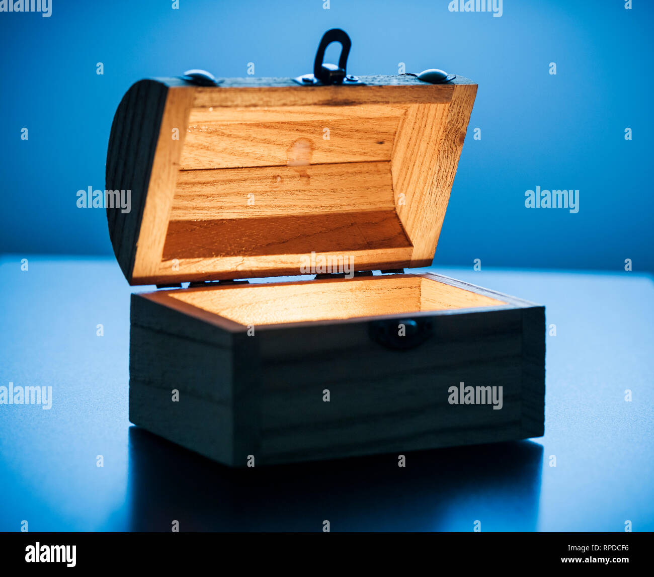 Small wooden chest inside illuminated on a blue ground Stock Photo - Alamy