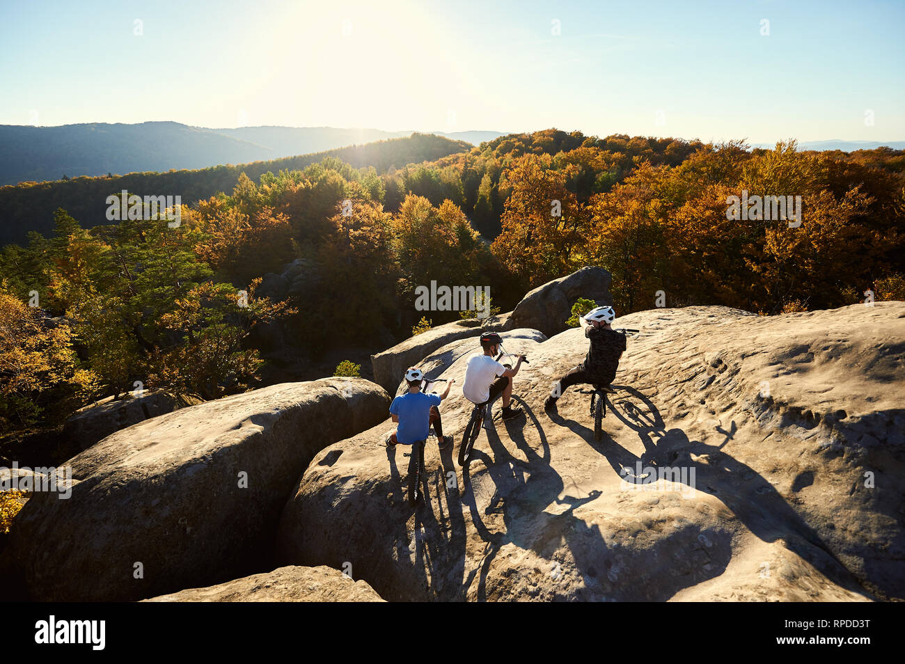 Back view of three young sportsmen with trial bicycles having a rest on ...