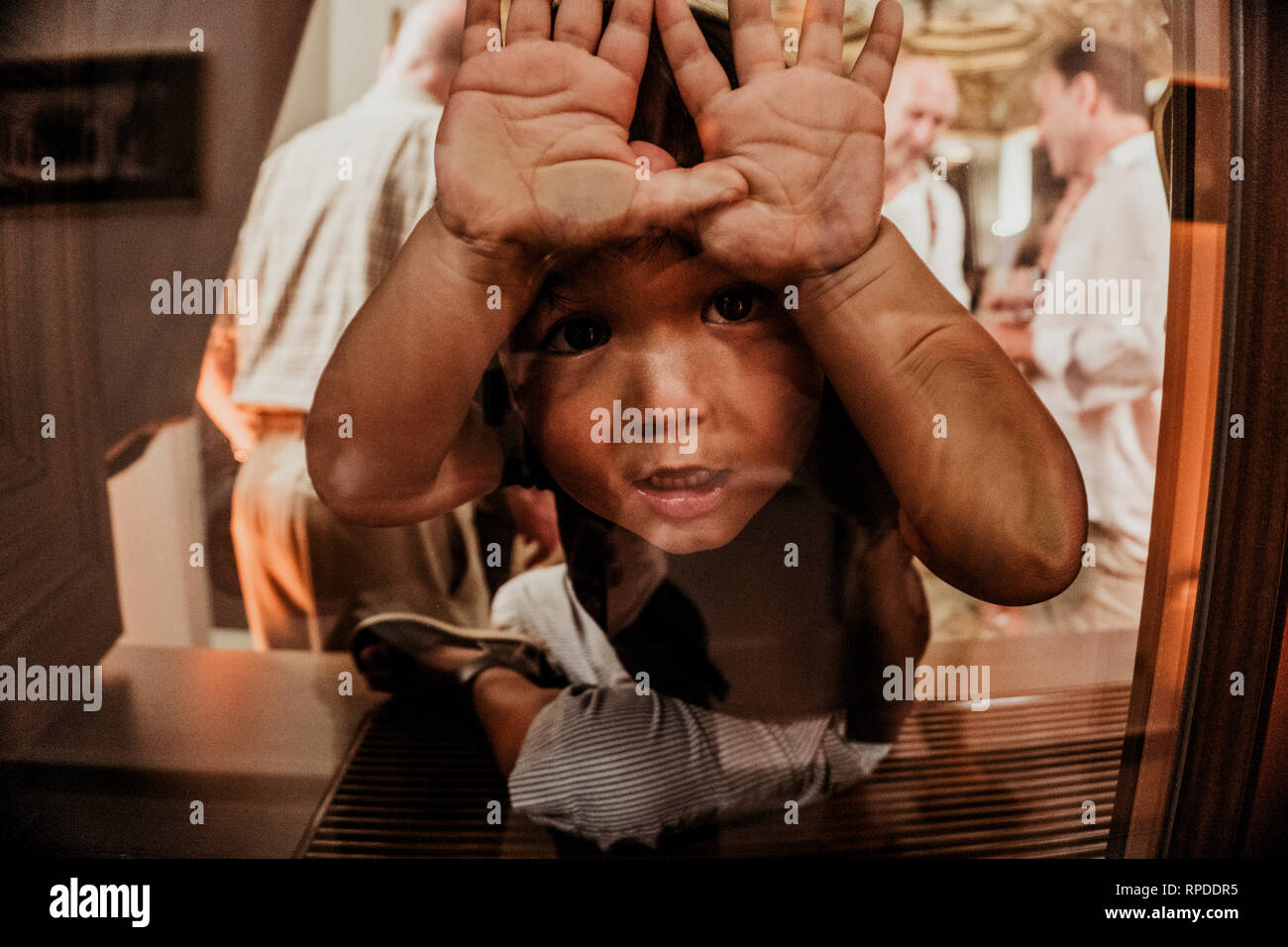 Small Child looking behind the window Stock Photo - Alamy