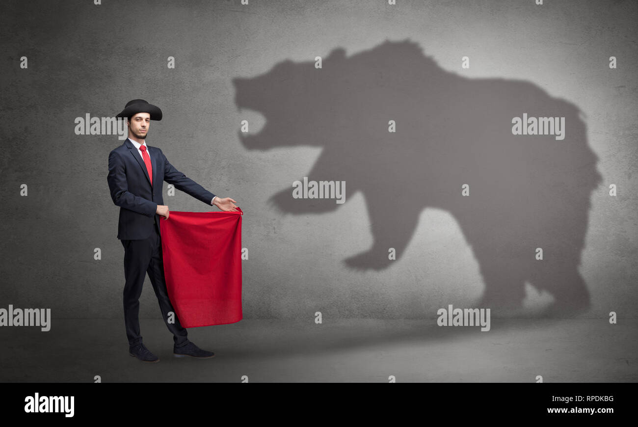 Businessman standing with red cloth in his hand and big bear shadow on ...