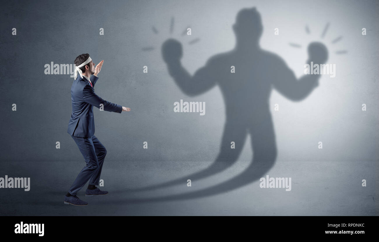 Businessman trying to fight with his unarmed shadow Stock Photo - Alamy