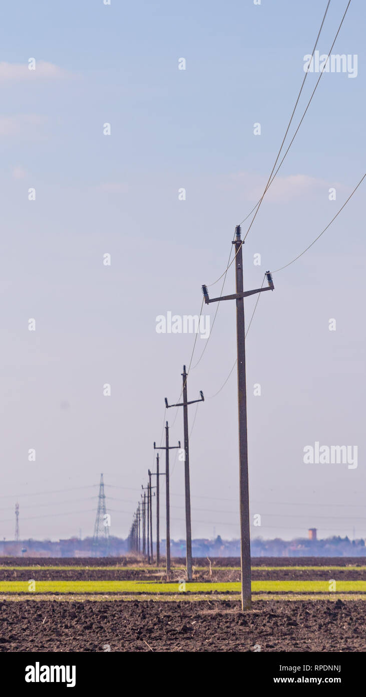 Old power transmission towers in line with blue sky and town in ...