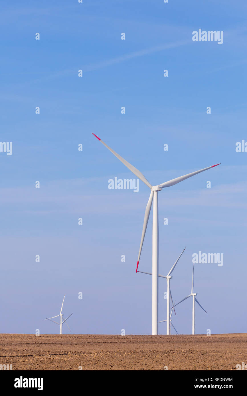Windmill turbine farm with partly cloudy blue sky in background ...