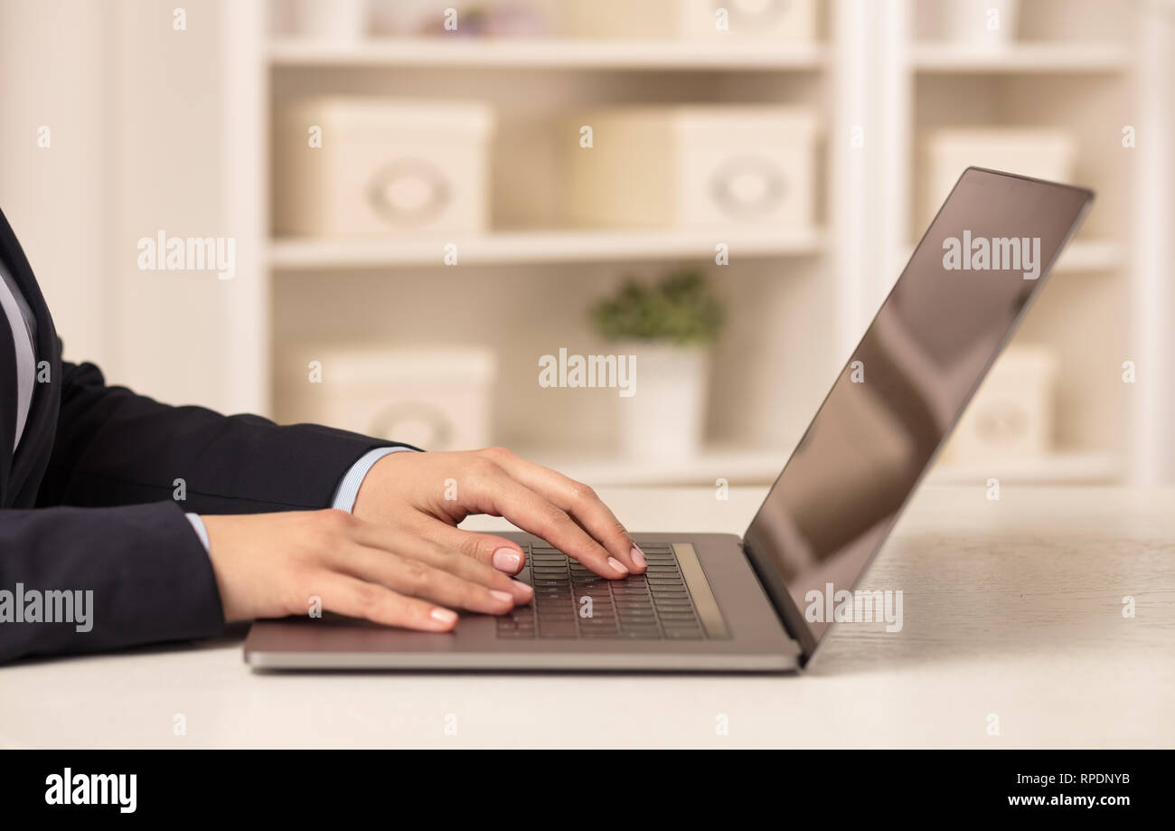 Business woman below chest working on her laptop in a cozy environment ...