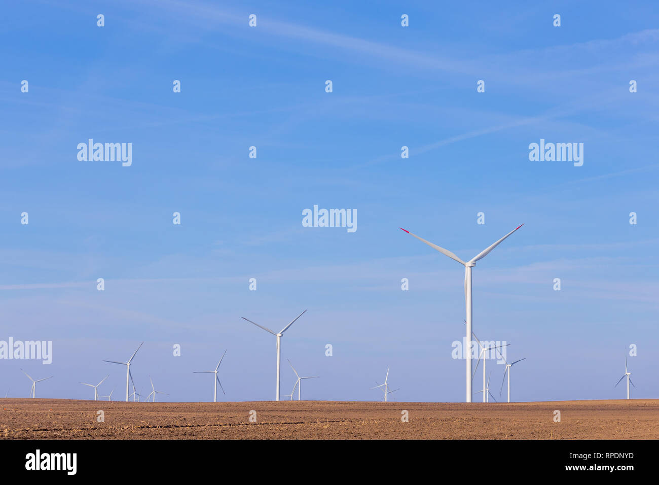 Windmill turbine farm with partly cloudy blue sky in background ...