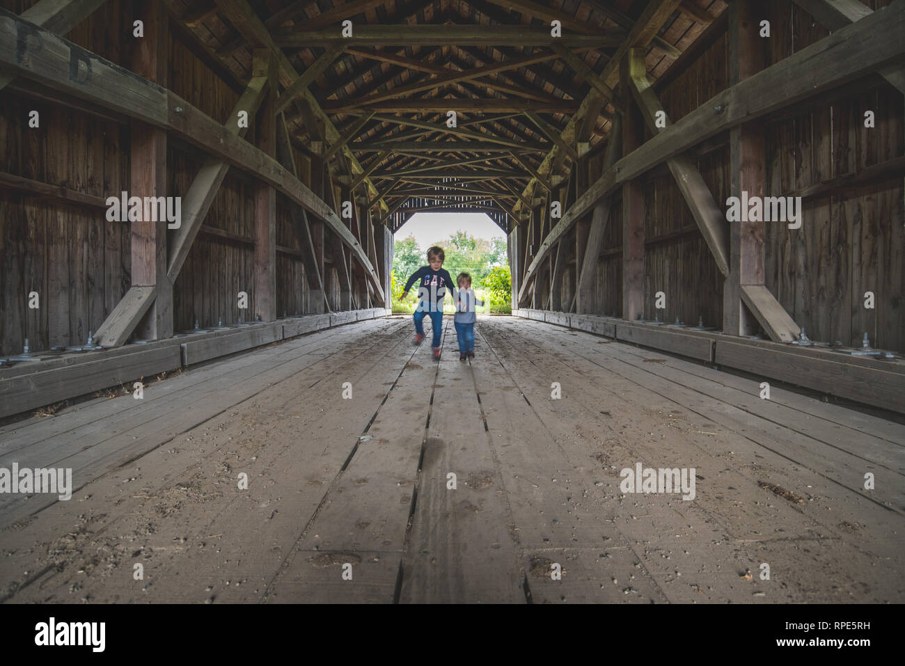 Brothers playing inside a covered bridge Stock Photo - Alamy
