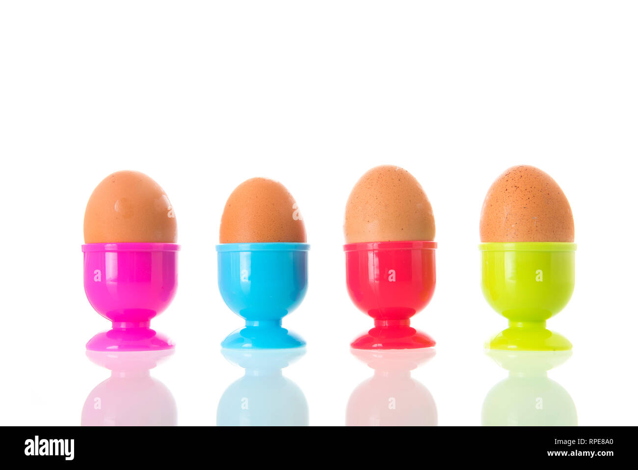 Colorful egg cups with eggs isolated over white background Stock Photo ...