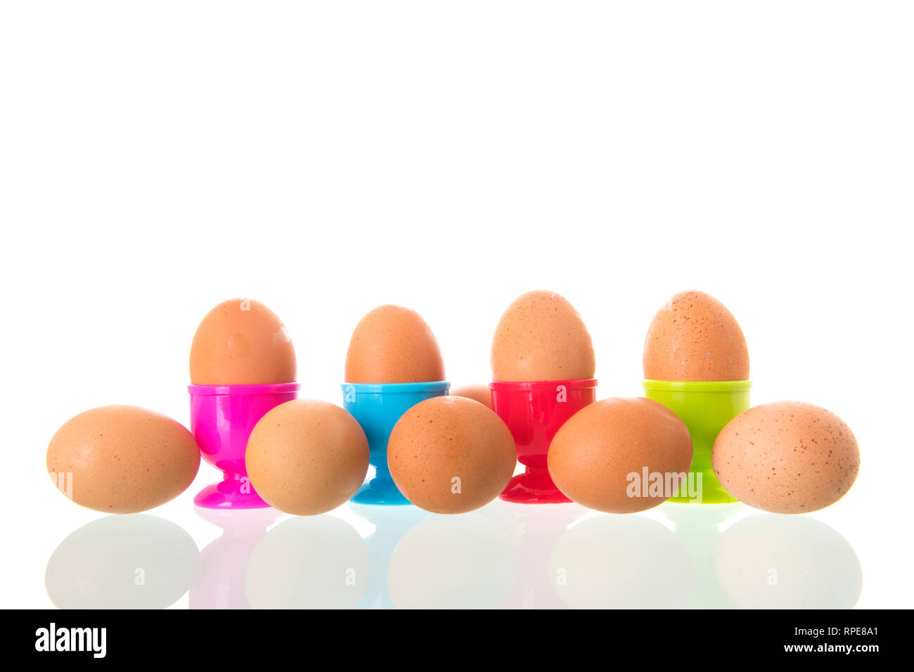 Colorful egg cups with eggs isolated over white background Stock Photo ...