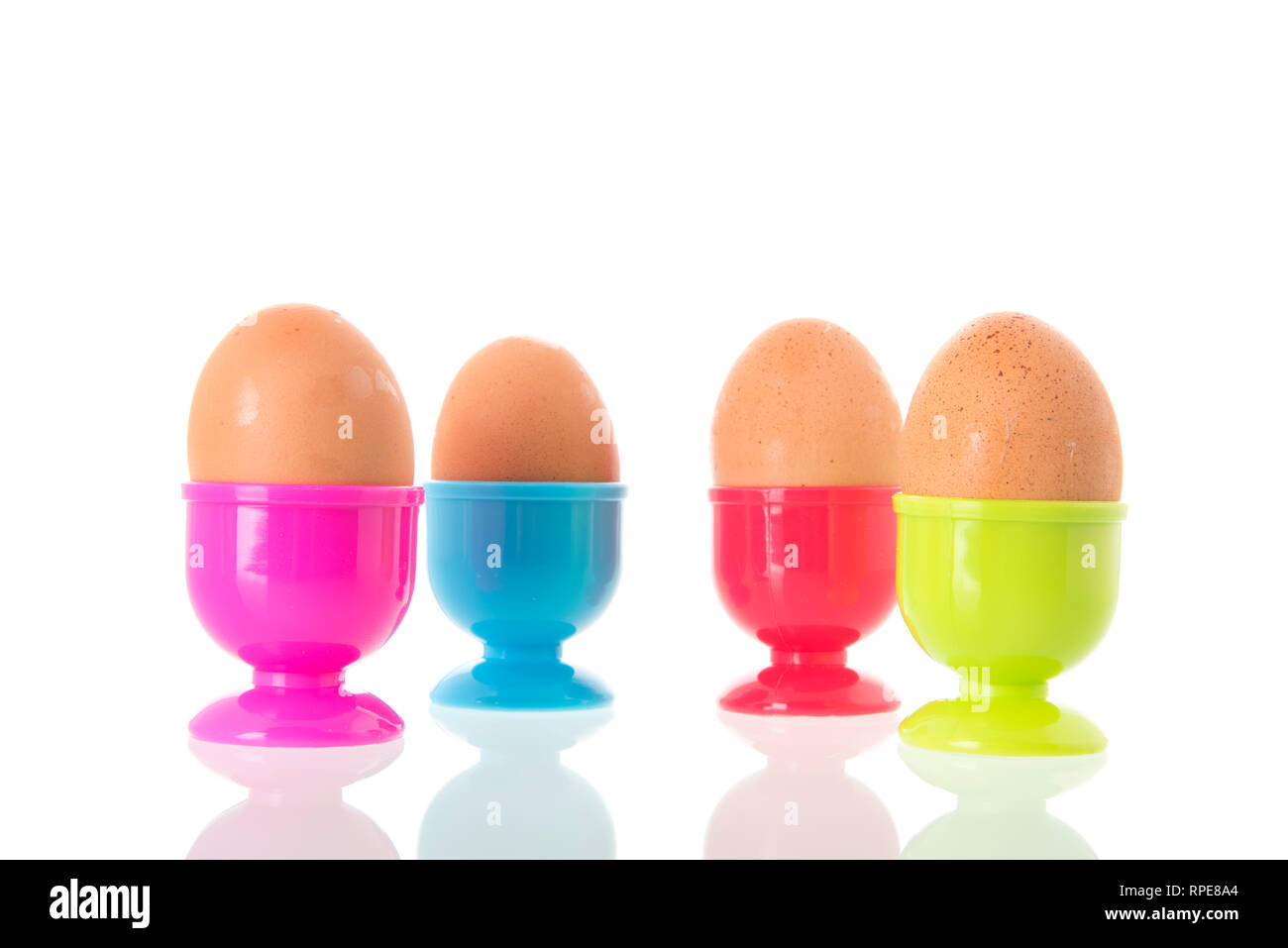 Colorful egg cups with eggs isolated over white background Stock Photo ...