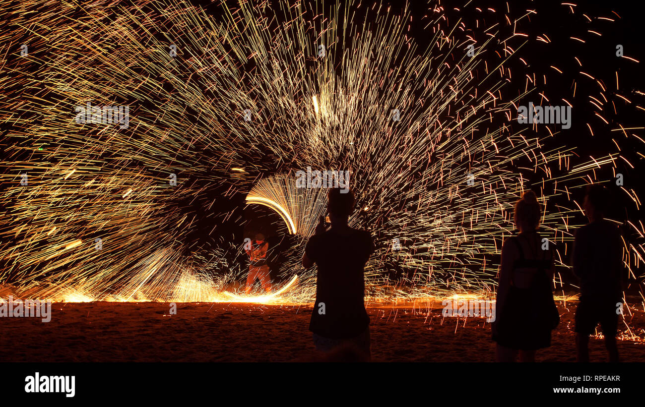 Sparks fly spiralling in an impressive display at a beach fire show ...