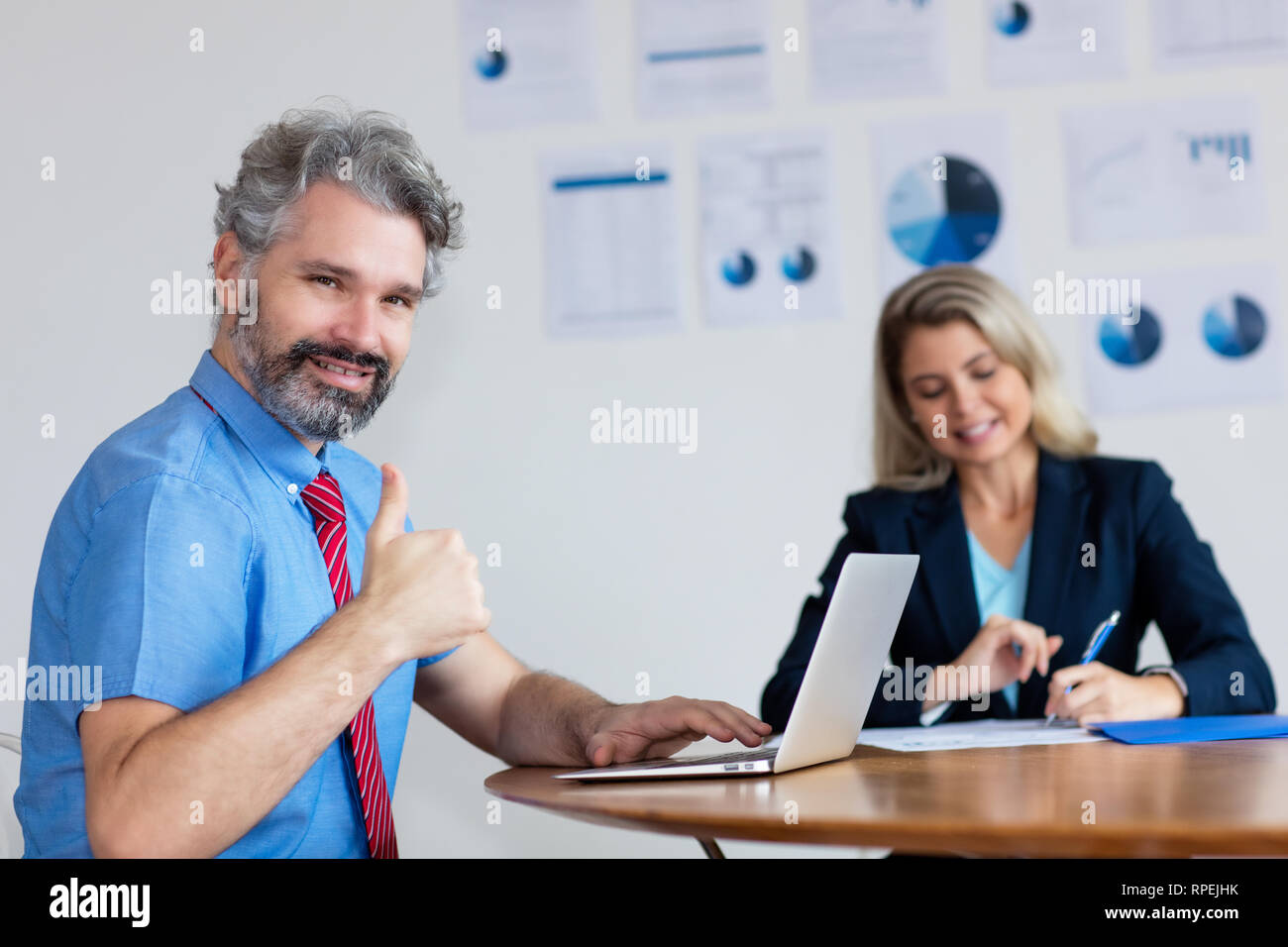 Successful german businessman with grey hair and computer at desk at ...
