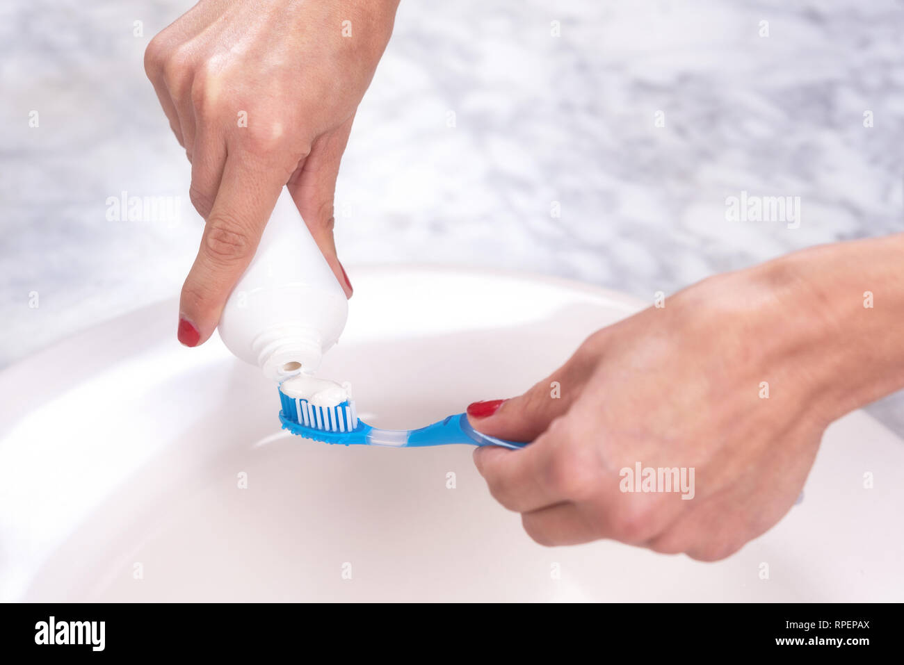 Woman holding a tooth brush putting toothpaste on it Stock Photo - Alamy