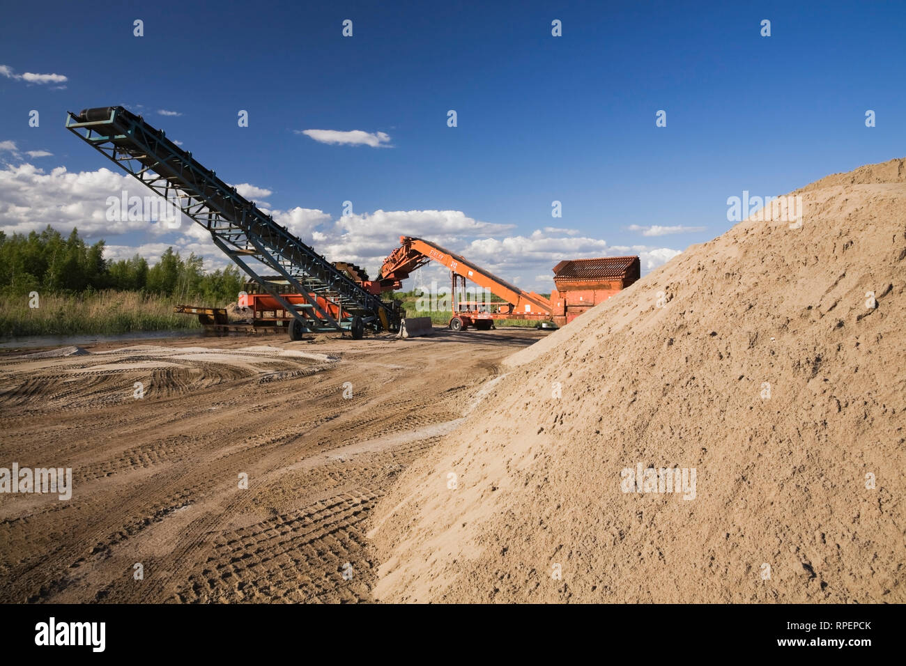 Stacking conveyor and a screener next to a mound of sand in a ...
