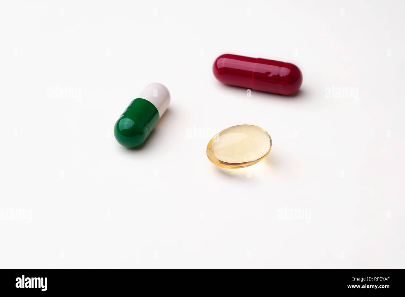 Three colored tablets and capsules on white background Stock Photo - Alamy