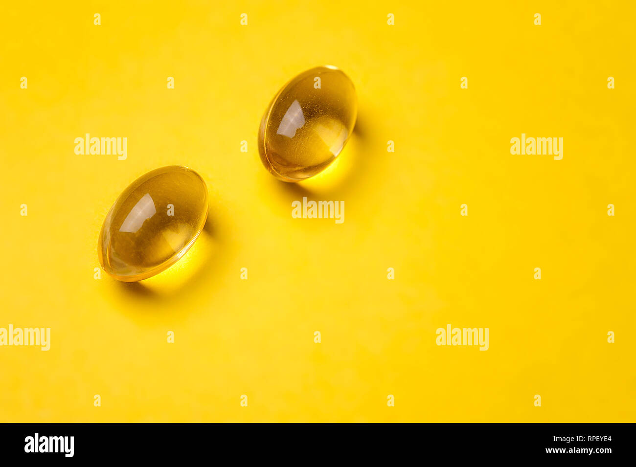Yellow transparent fish oil pills on yellow background Stock Photo - Alamy