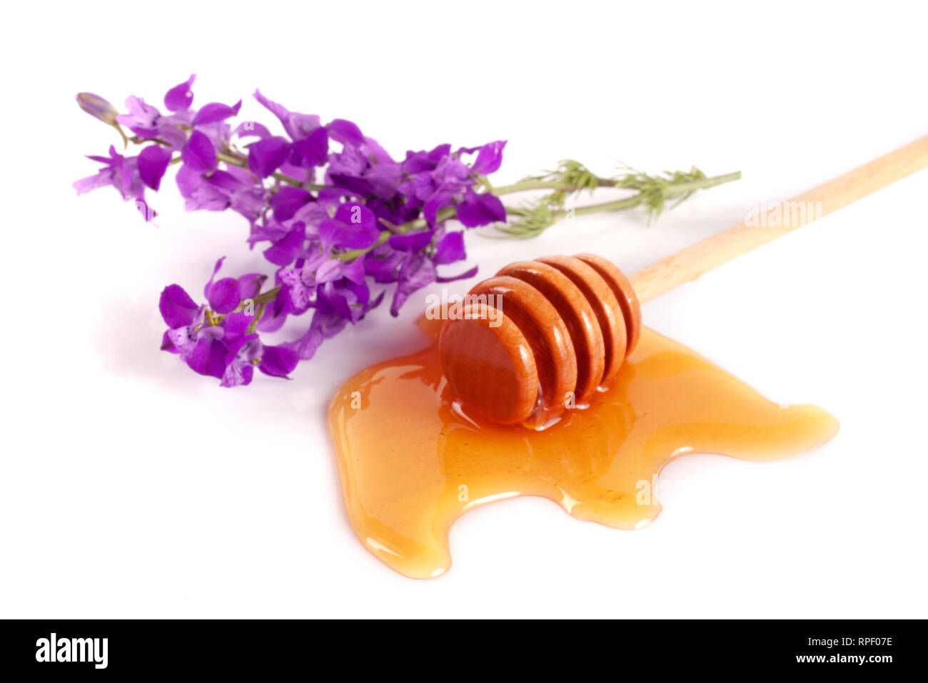 Honey stick with flowing honey and wildflowers isolated on white ...