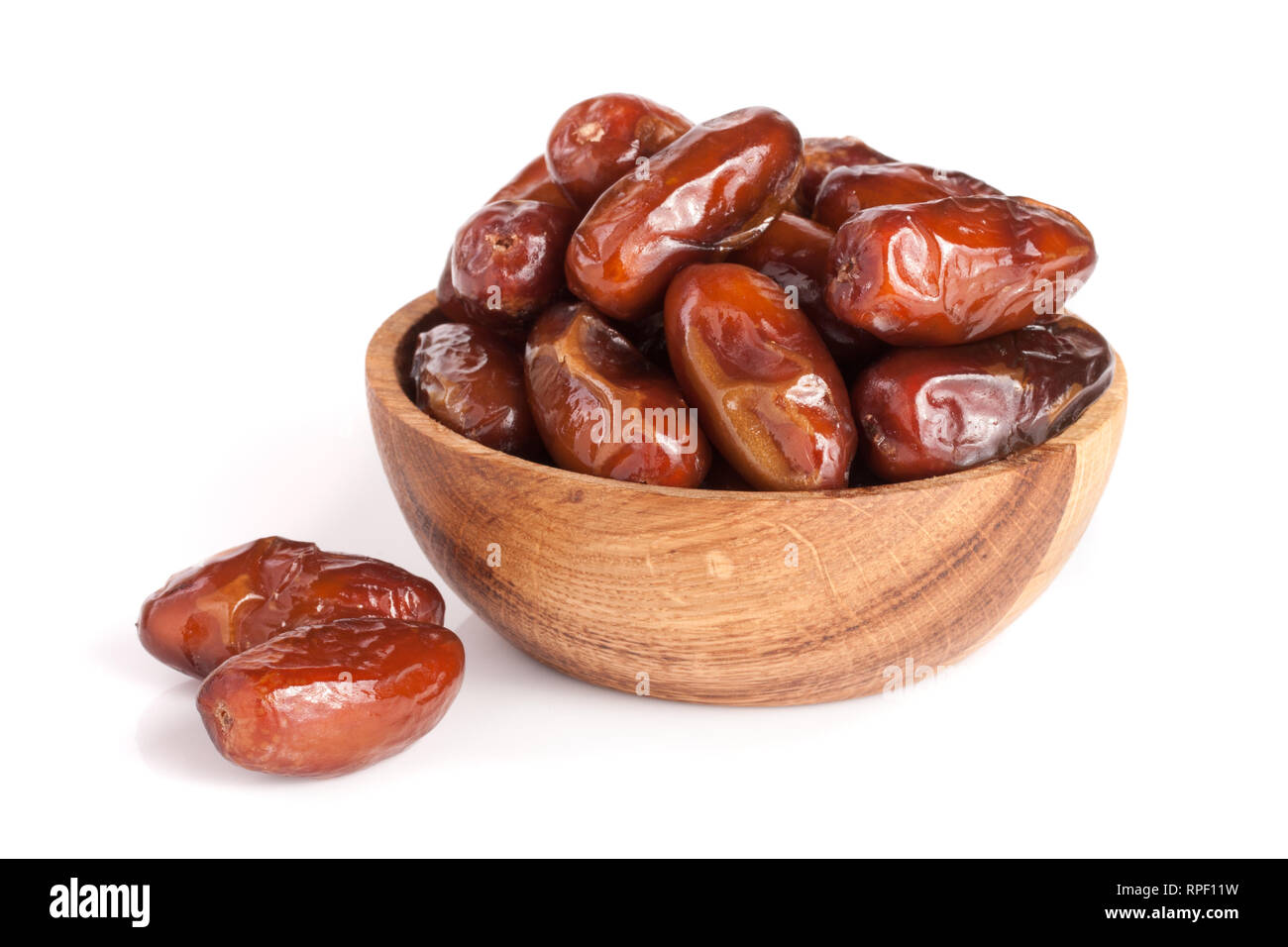 Dates in a wooden bowl isolated on white background Stock Photo - Alamy