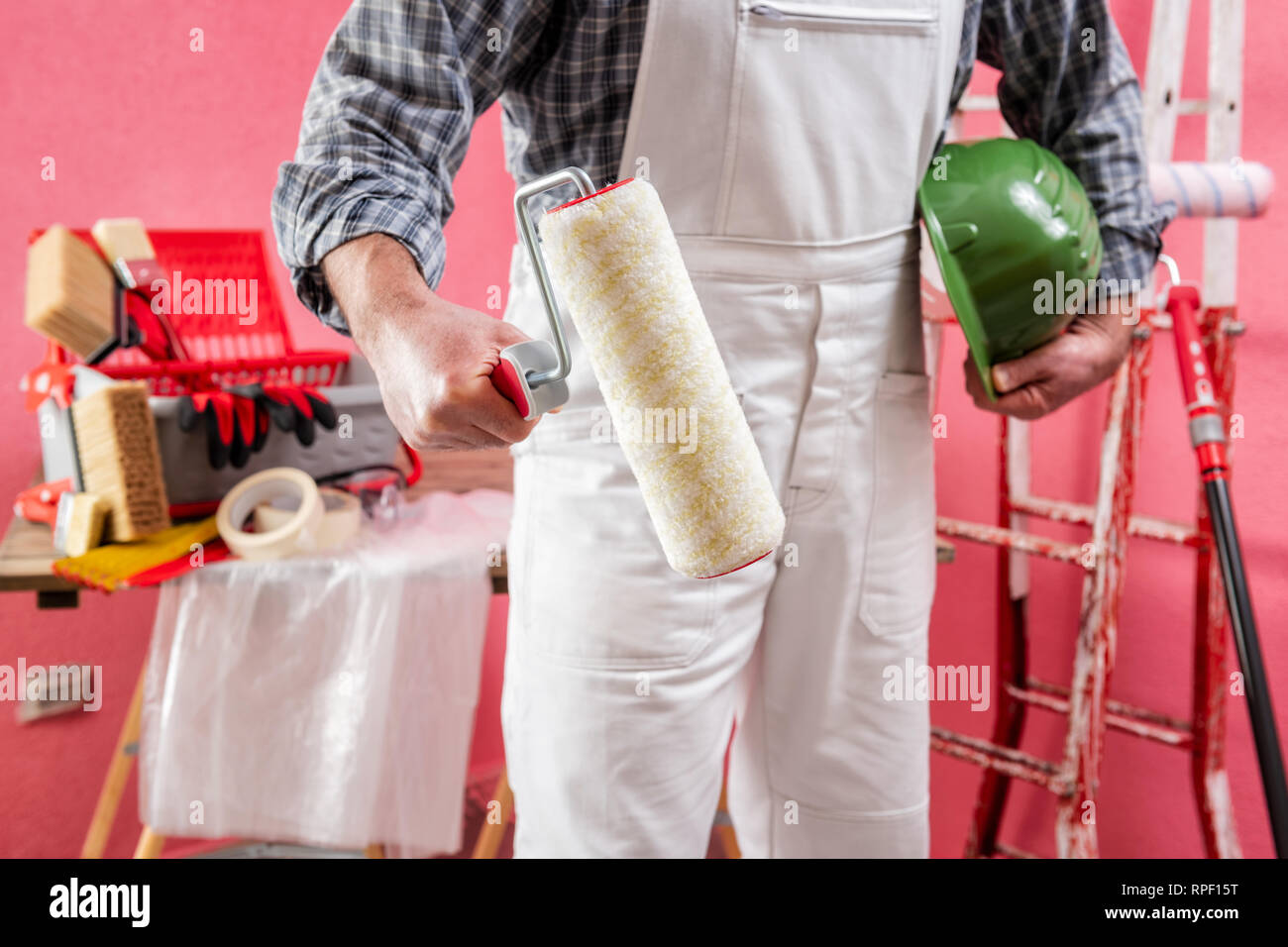 Caucasian house painter worker in white work overalls, with the roller ...