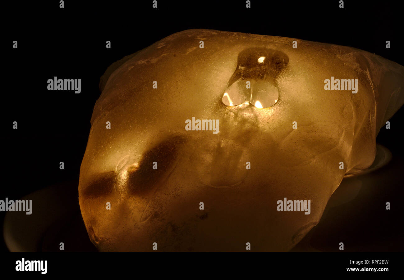 Candle fire is melting the ice creating beautiful reflection in the ...