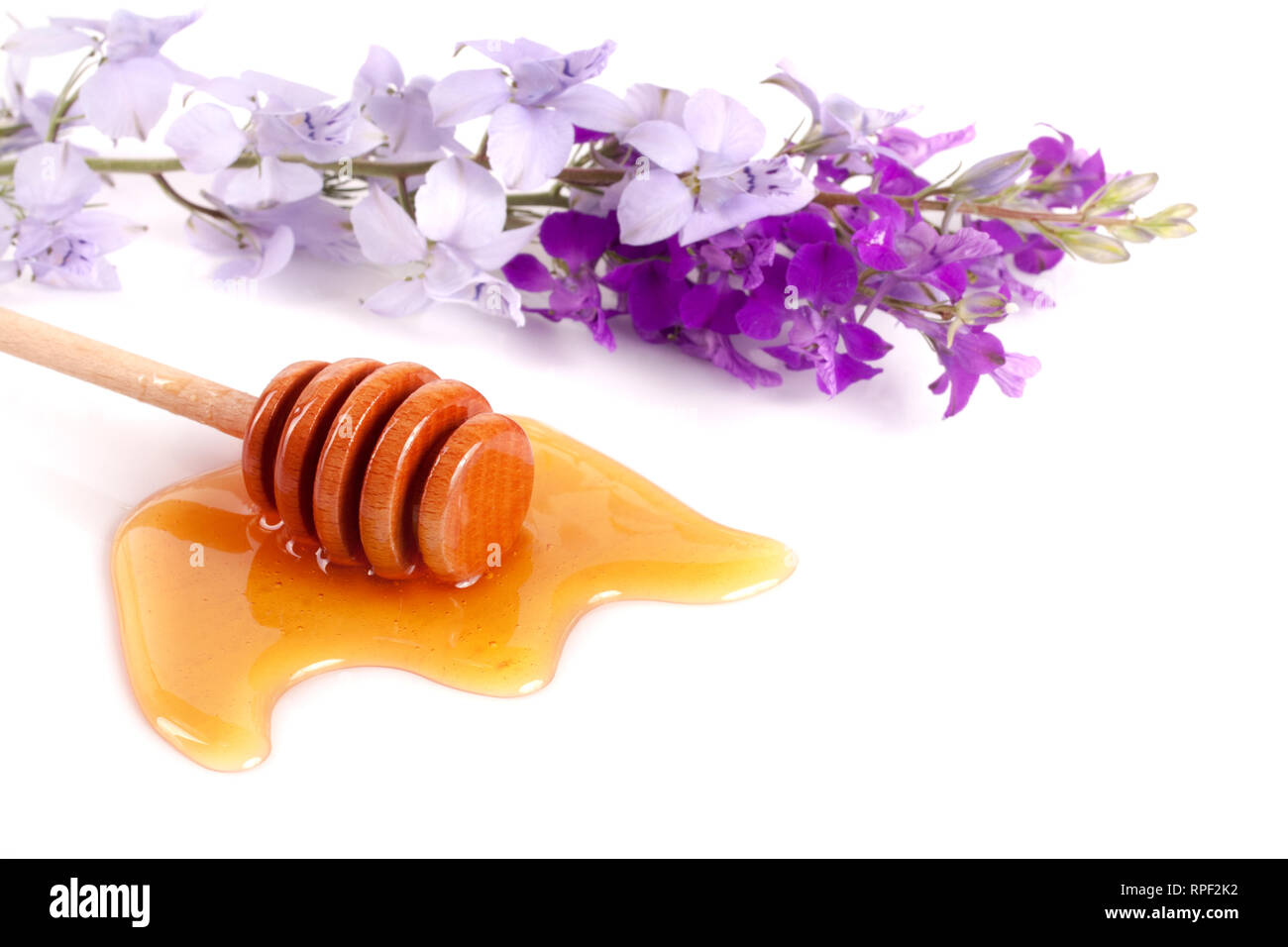 Honey stick with flowing honey and wildflowers isolated on white ...