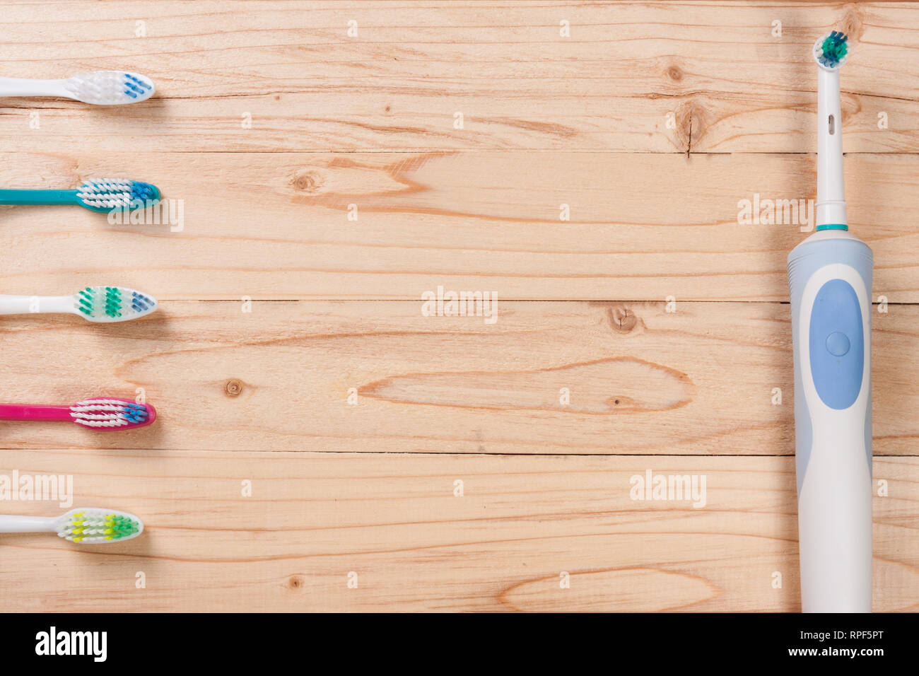 electric and manual toothbrushes on the light wooden background with ...