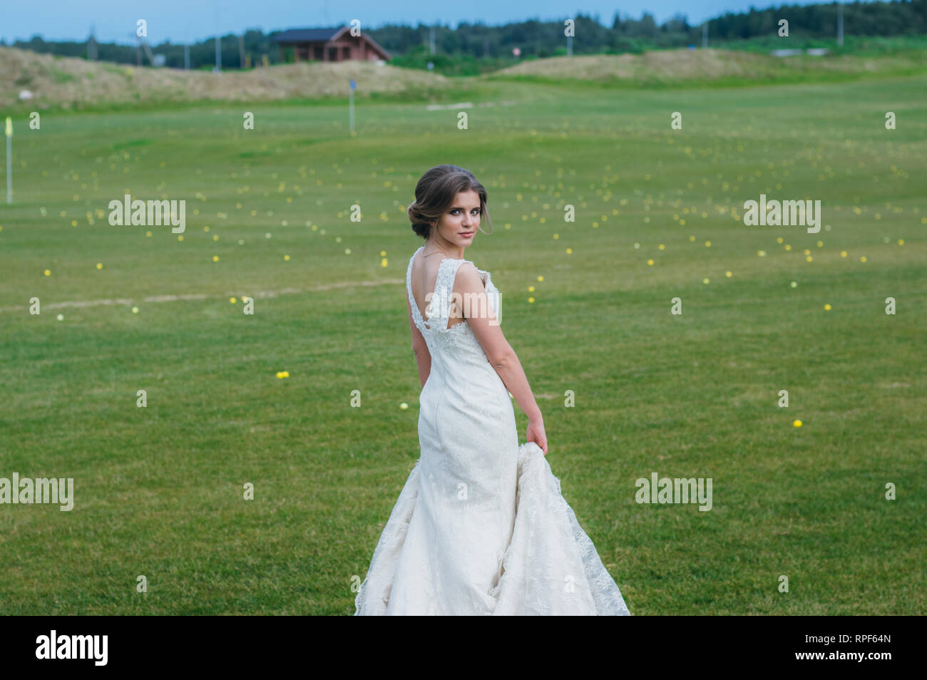 Beautiful bride in wedding dress on the green field of the golf club ...