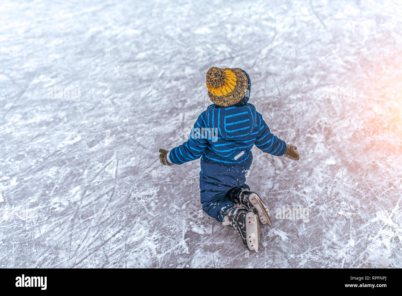 Small boy of 2-3 years old, wearing skirt, fell on ice his skates ...