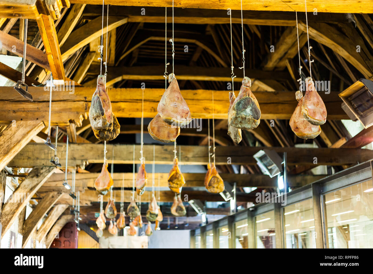 Hooked ham on wooden beams that hang from the ceiling. Traditional way ...