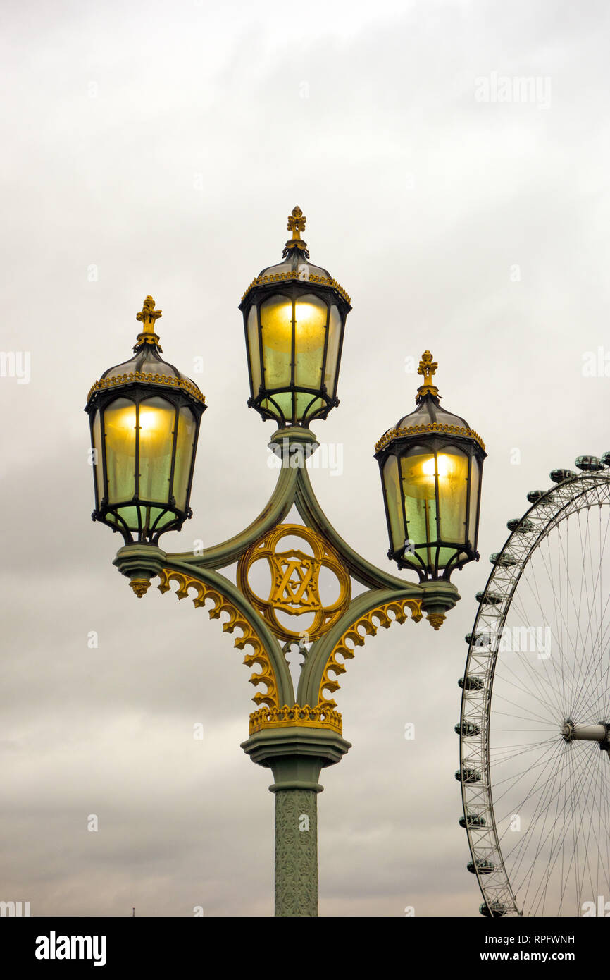 Ornate triple headed cast iron lamp post with gas lights lit on ...
