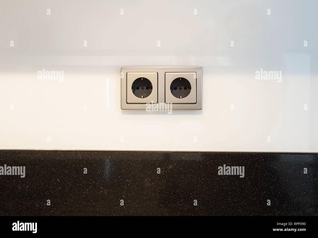 European white electrical outlet socket and black cable plugged in ...