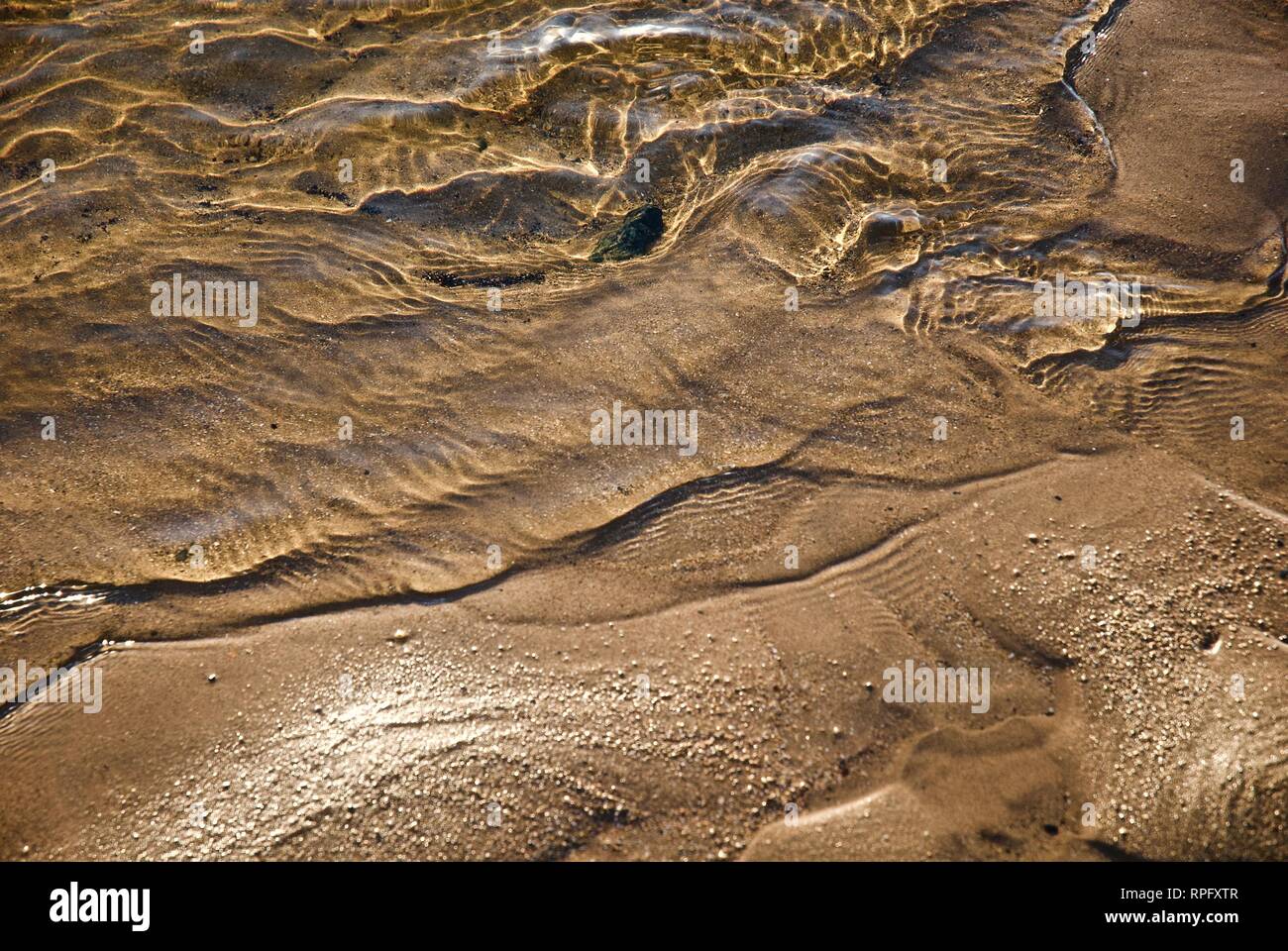 Sea water makes undulating abstract patterns and shapes in brilliant ...