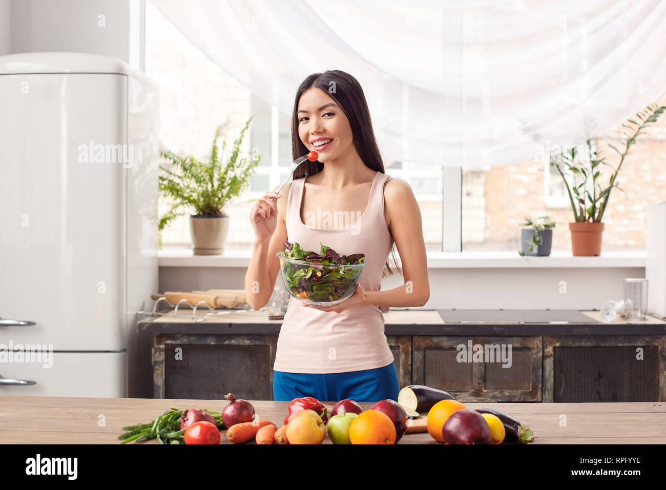 Young girl at kitchen healthy lifestyle standing eating salad looking ...