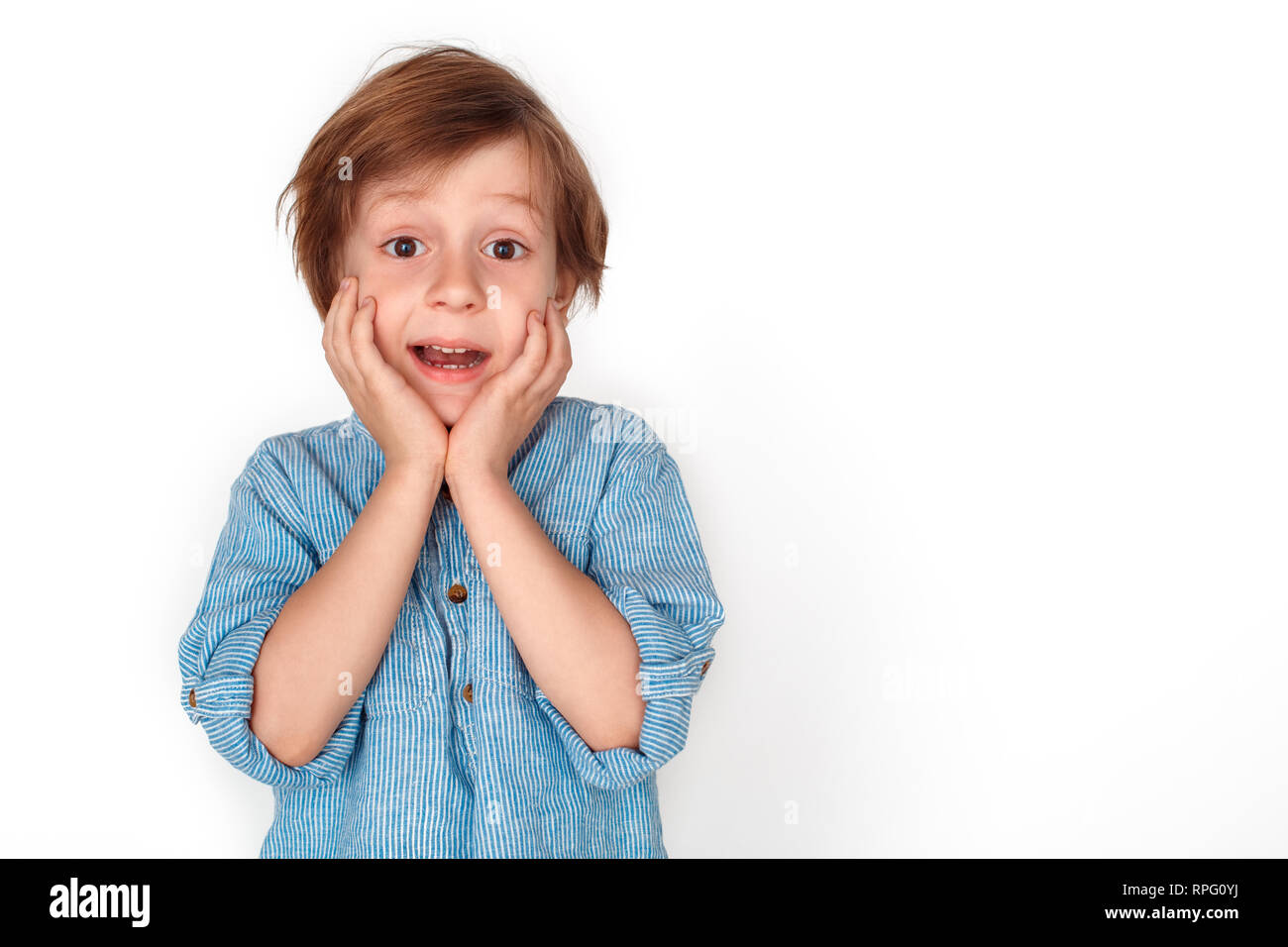 Boy studio standing isolated on grey touching face looking camera ...