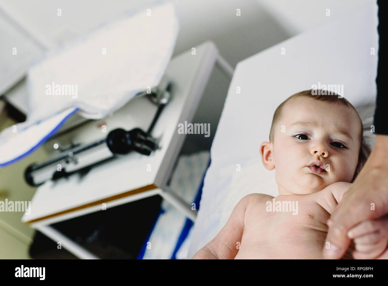 Baby in a pediatric clinic ready to be weighed on a scale during his ...