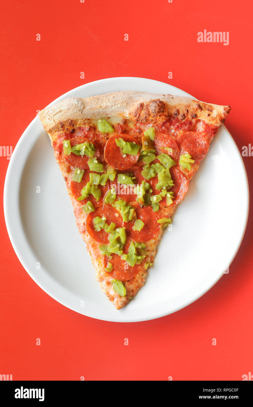 Slice of green chile and pepperoni pizza on a white plate Stock Photo ...