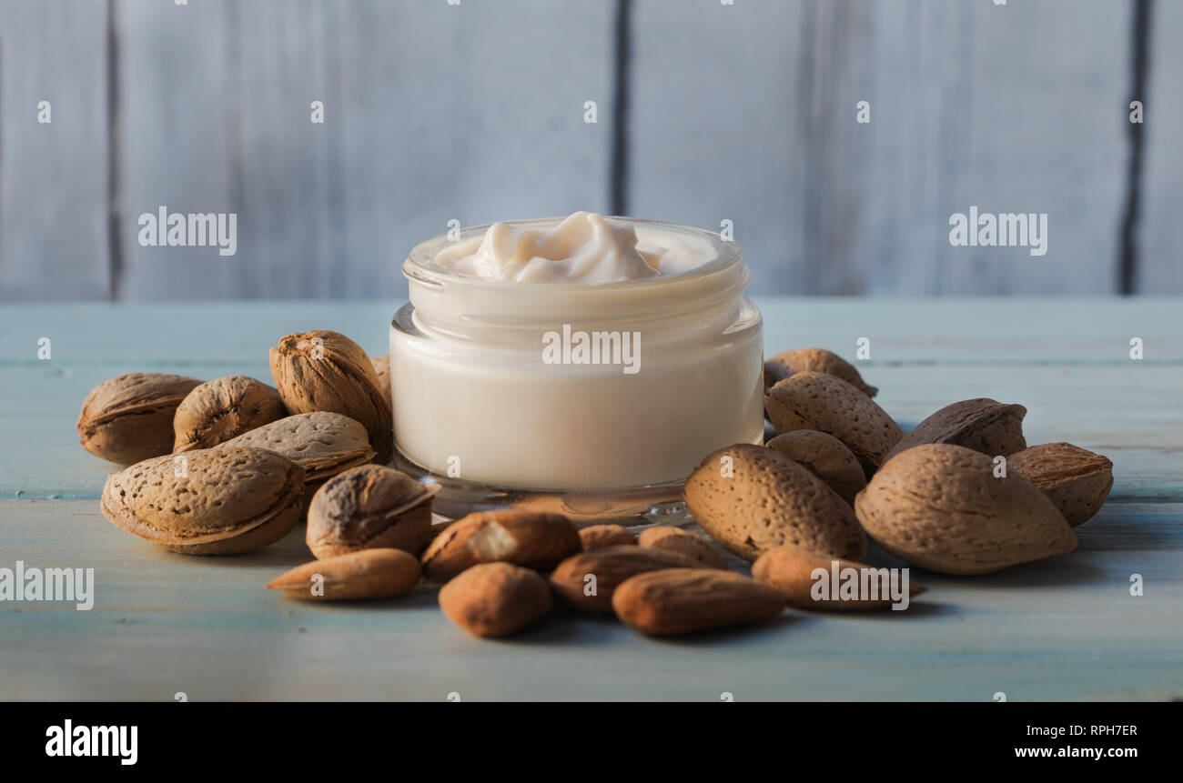 Homemade facial cream of almond oil surrounded by natural almonds, n a ...