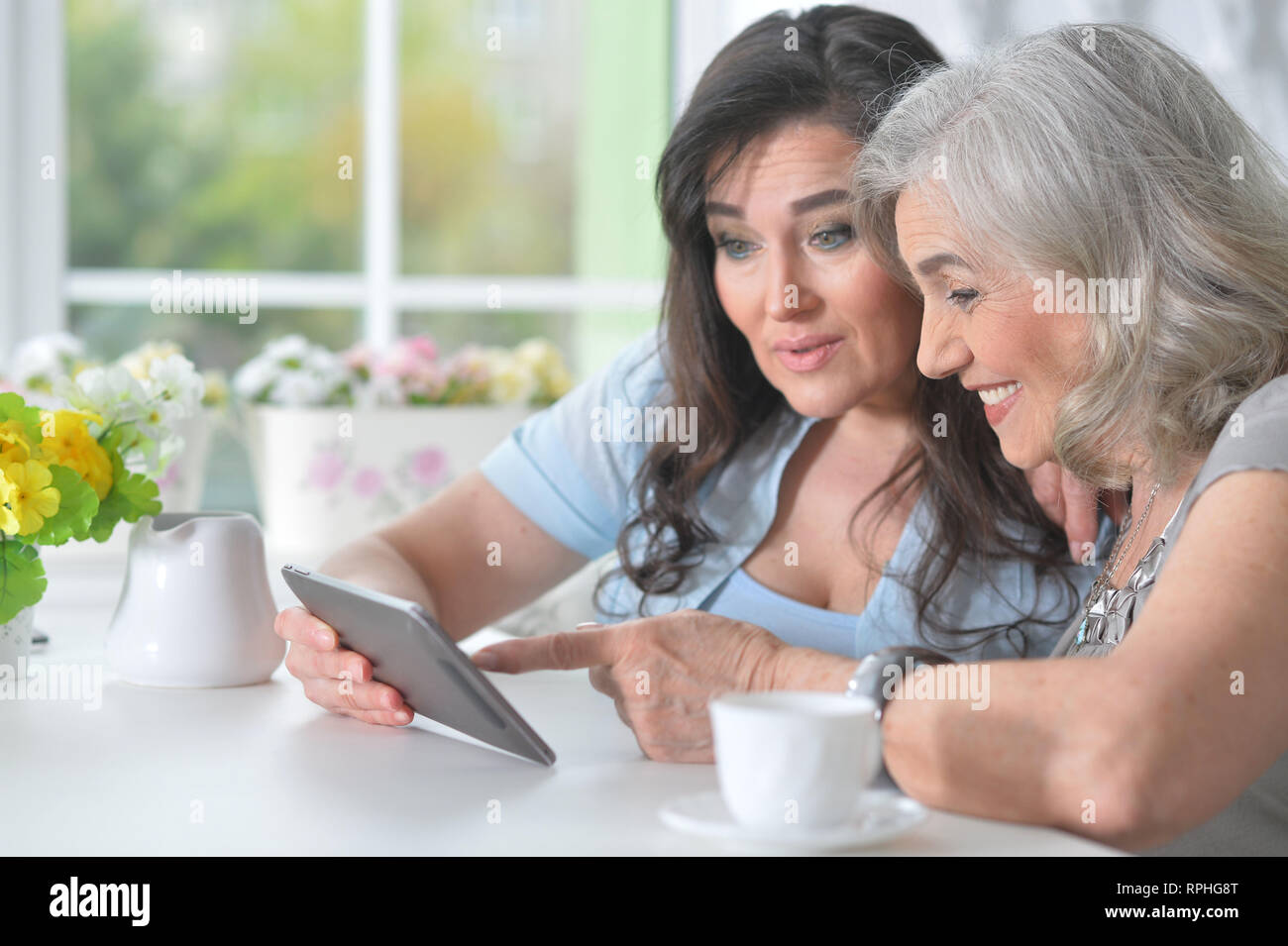 Two mature women using modern tablet at home Stock Photo - Alamy