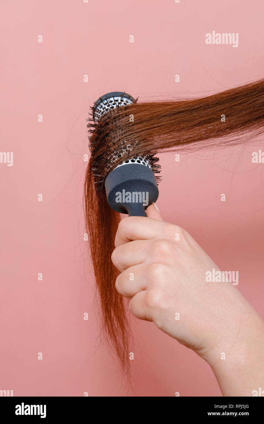 comb for volume of female hair in woman hand on pink background Stock ...