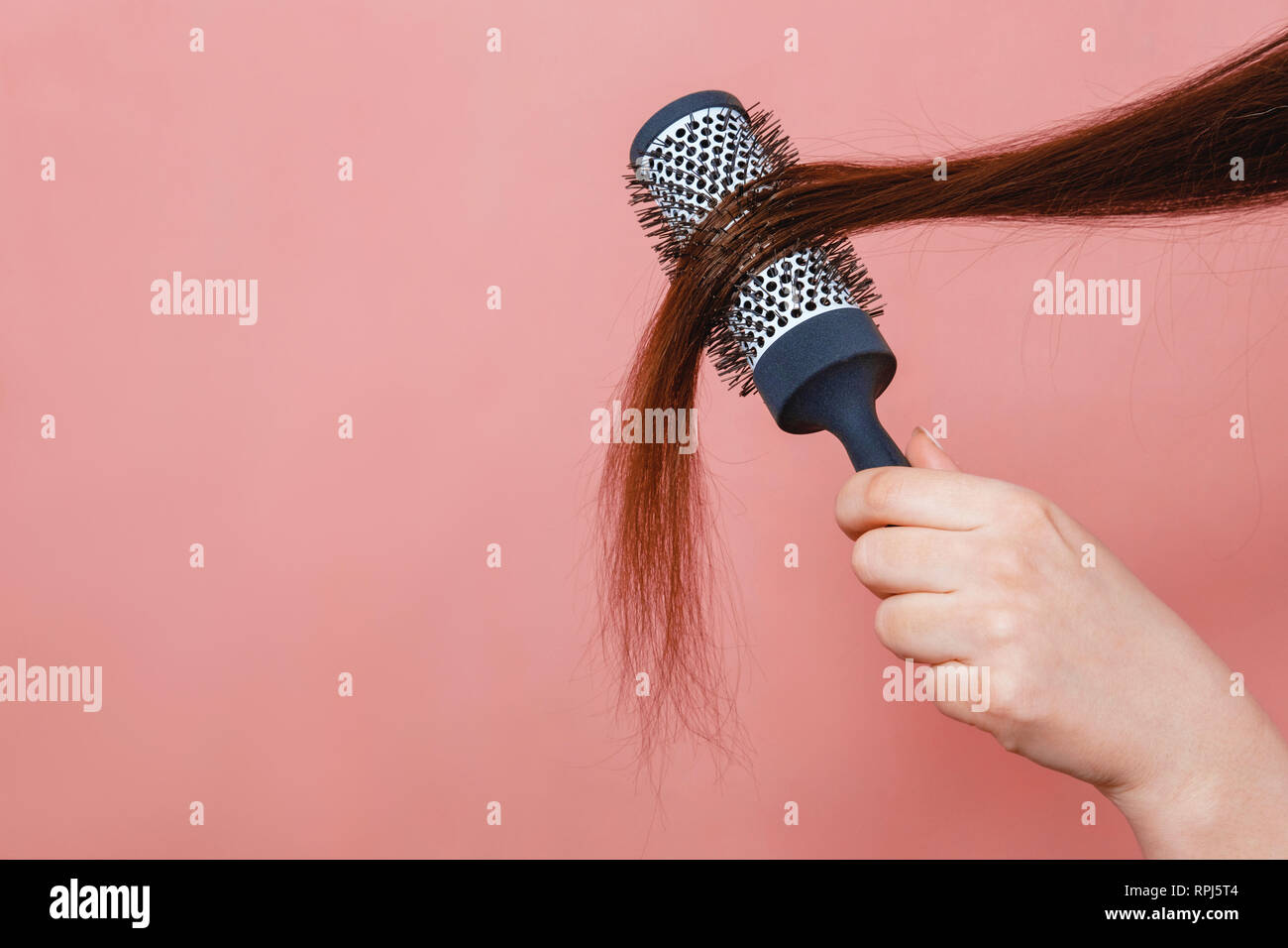 comb for volume of female hair in woman hand on pink background Stock ...