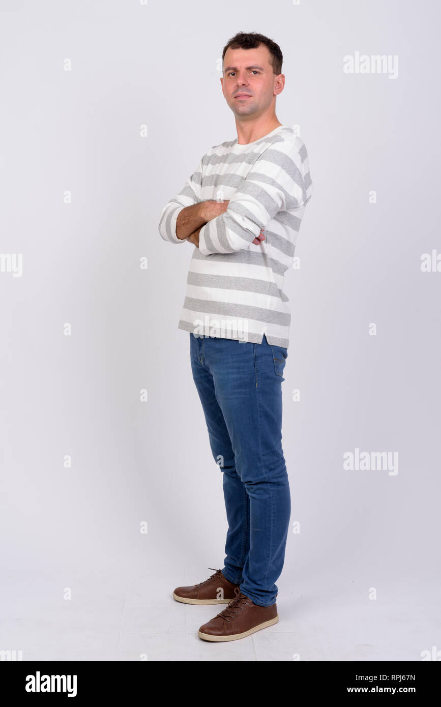 Full body shot profile view of man looking at camera with arms crossed ...