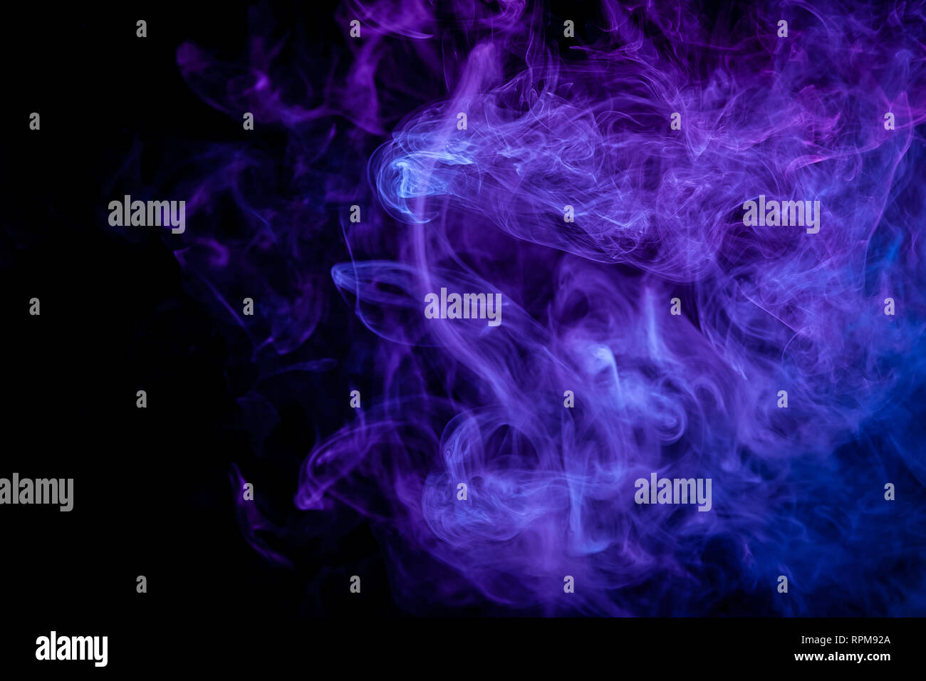Close up swirling purple and blue smoke on black isolated background ...