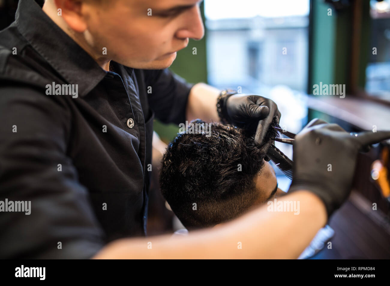 Close up of man getting trendy haircut at barber shop. Male hairstylist ...