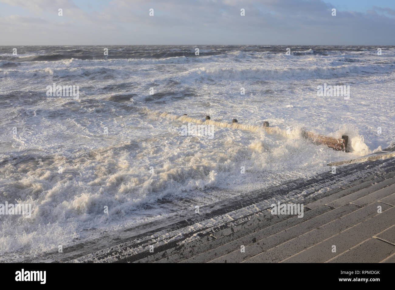 Rough sea impacting wooden groyne and concrete stepped revetment ...