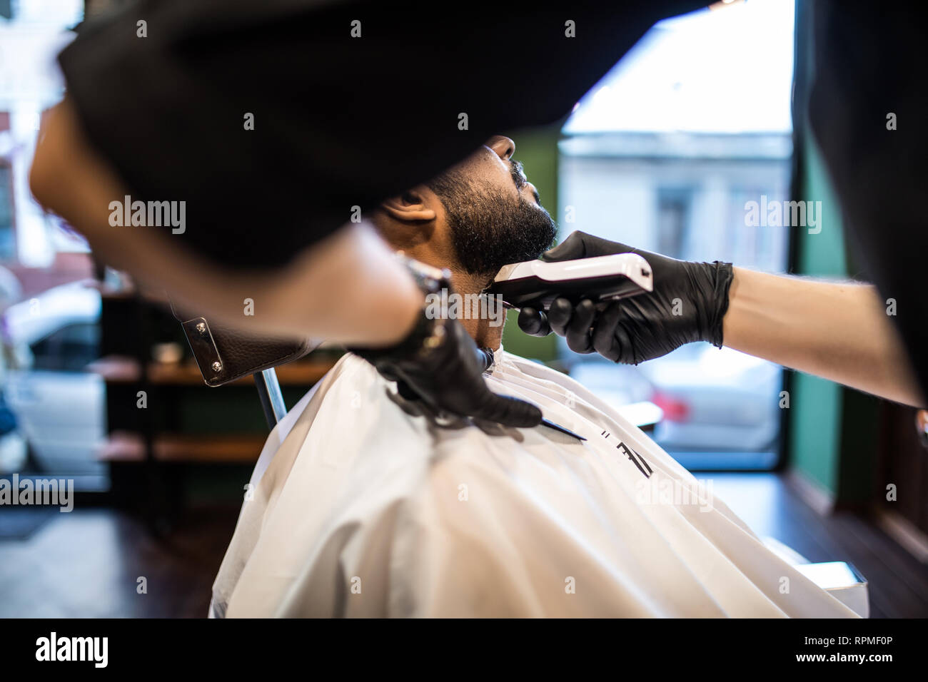 Grooming of real man. Side view of young bearded man getting beard ...